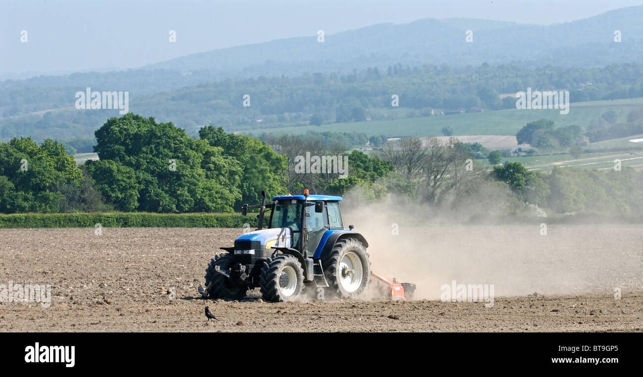 Tractor working on dry land in Sussex pulverising the soil and creating ...