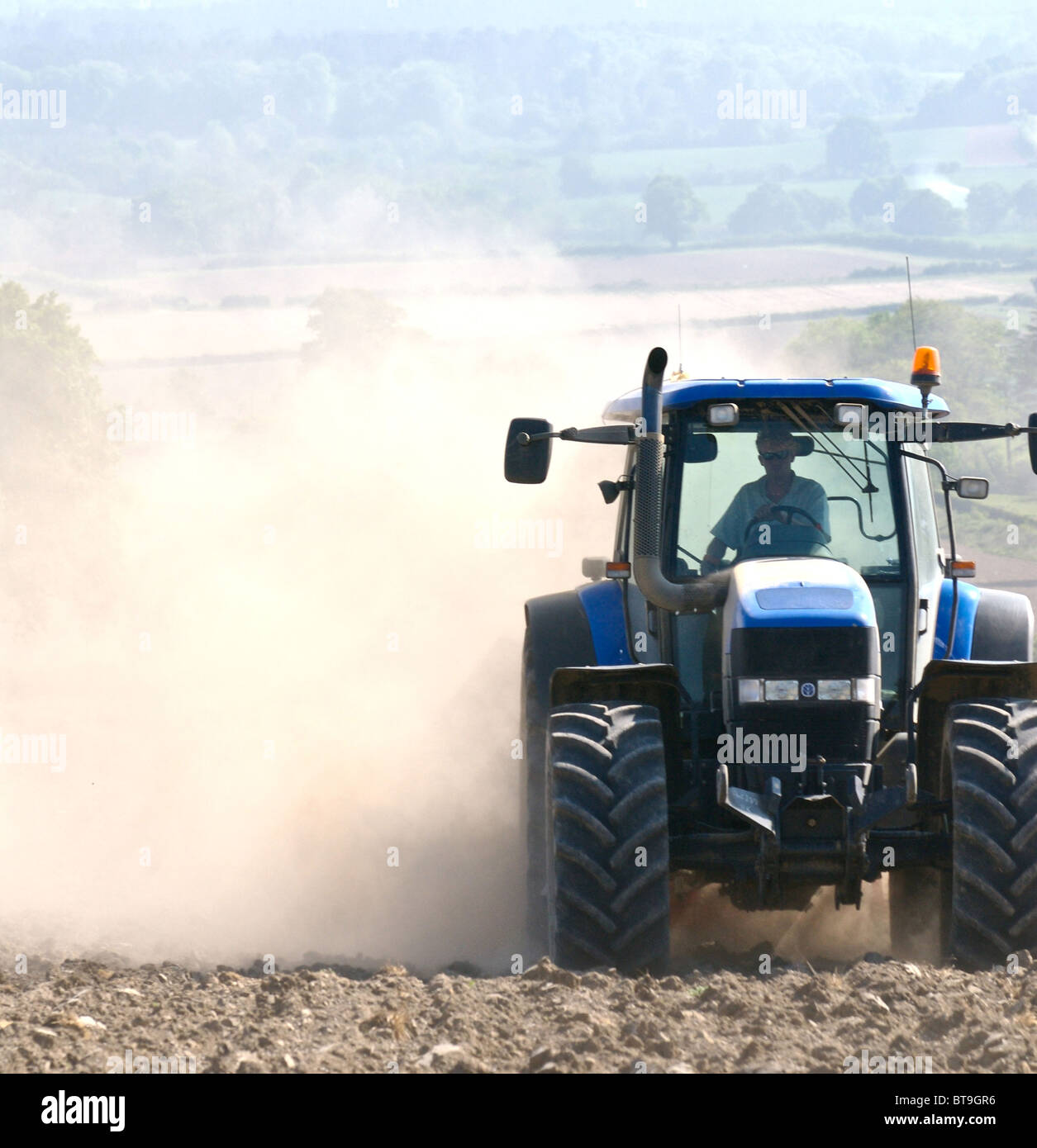 Tractor working on dry land in Sussex pulverising the soil and creating ...