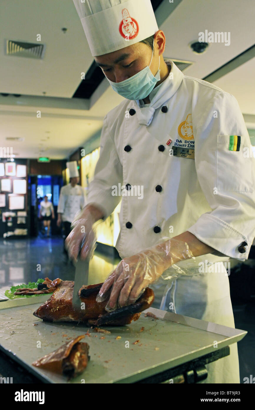 Peking duck carved by a chef wearing a surgical mask at Dadong ...