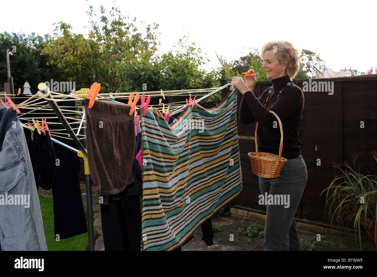 Middle aged woman hanging out her clean washing on whirl gig washing ...