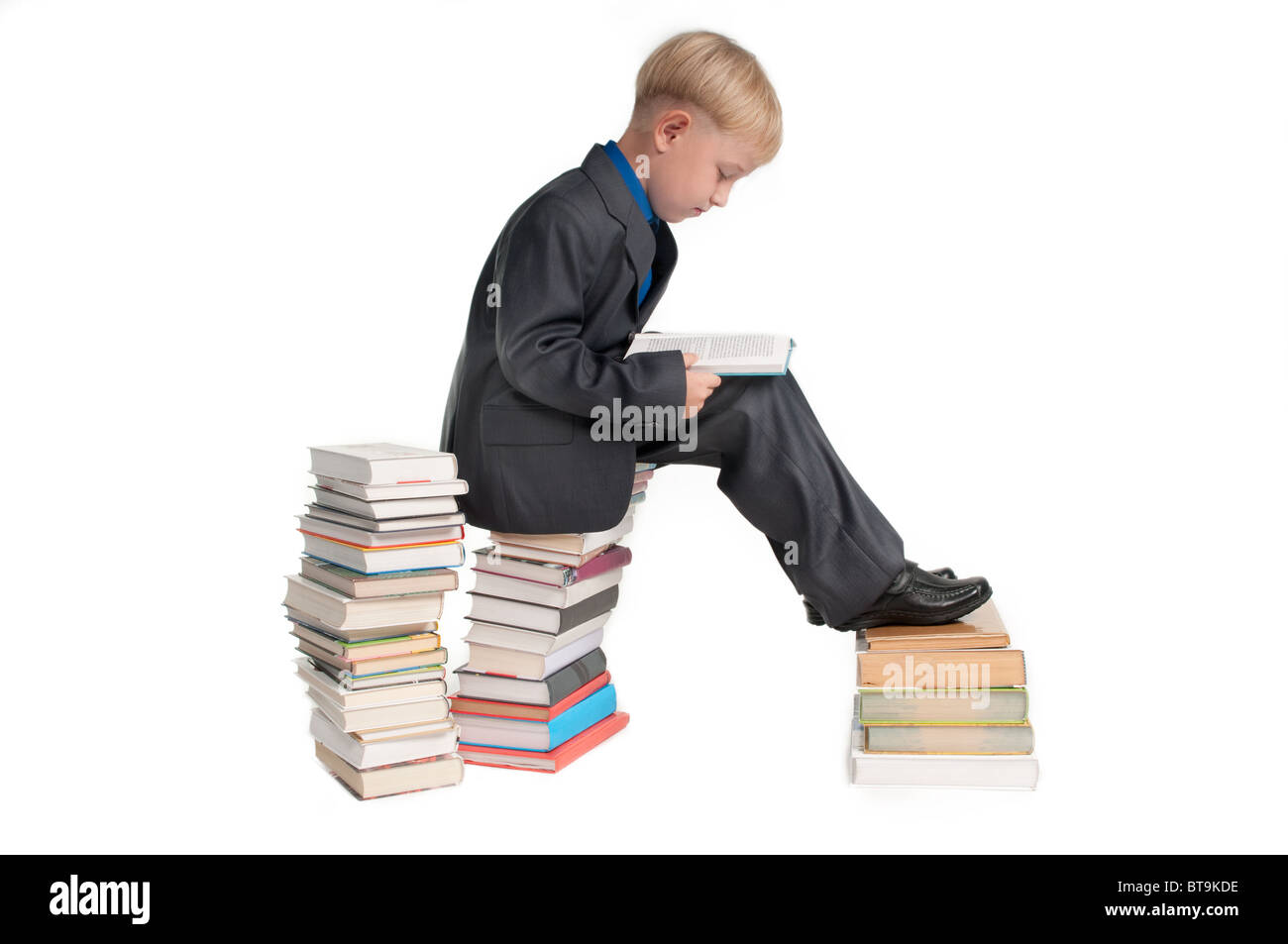 Boy studying his lessons while sitting on a pile of books Stock Photo ...