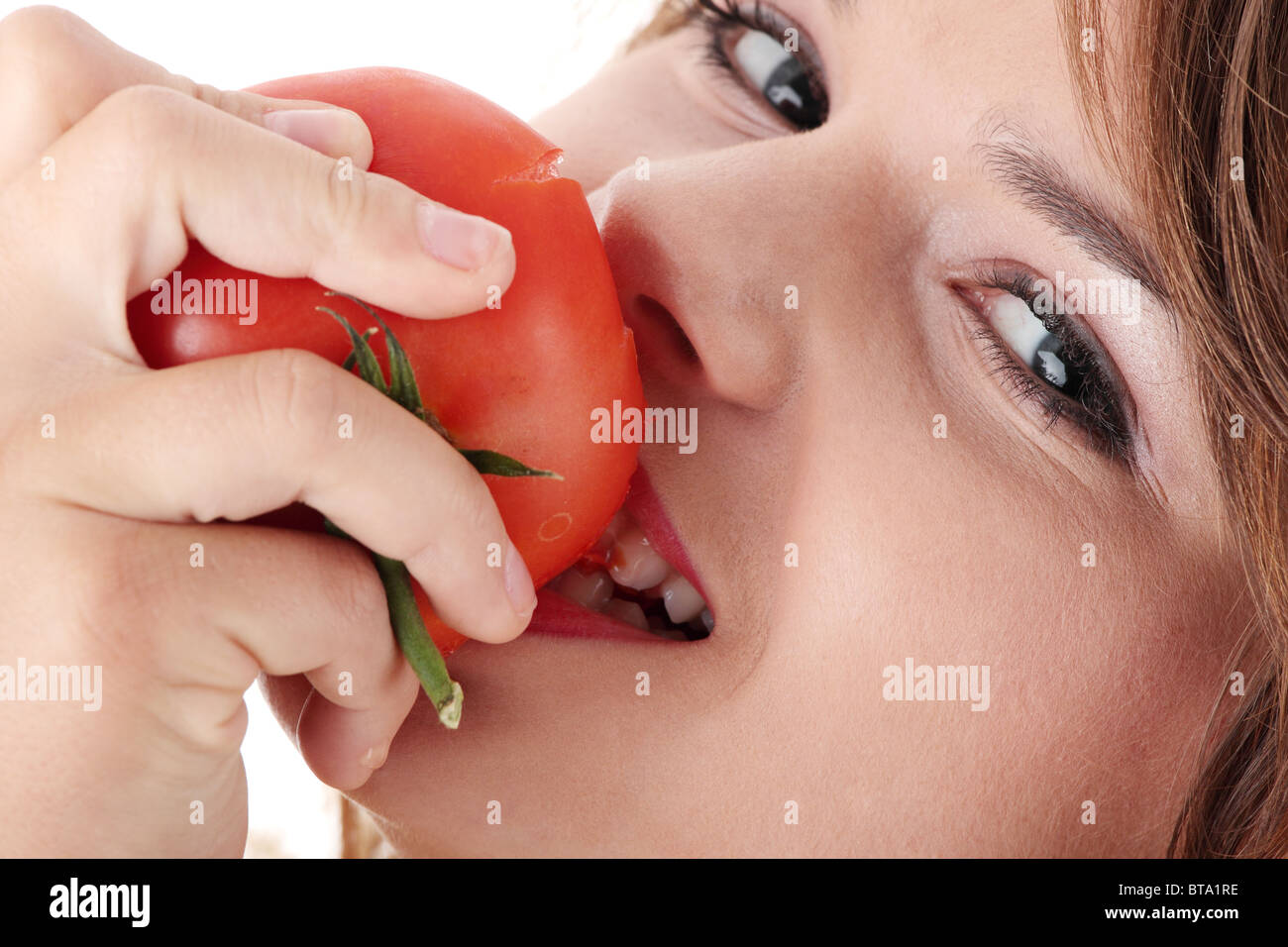 Young woman eating tomato isolated on white background Stock Photo - Alamy