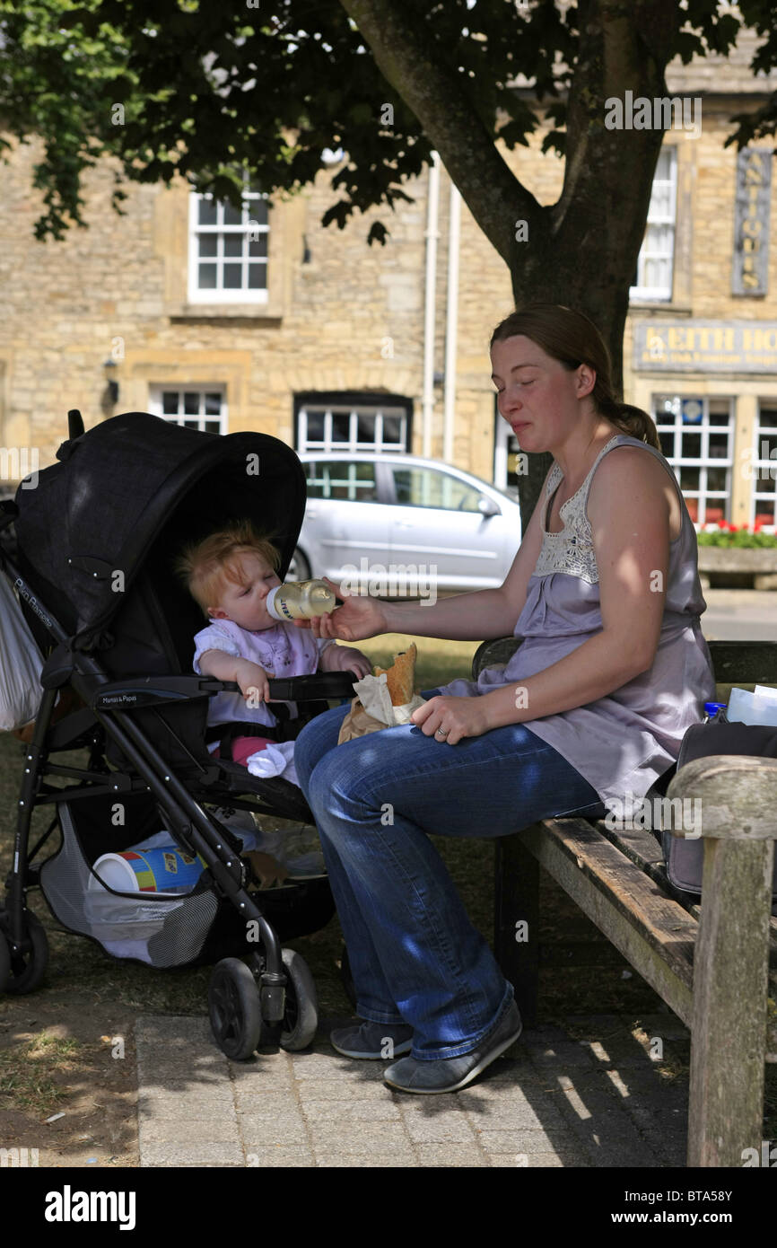 Young Mum feeding her baby under a tree shading themselves from the hot ...