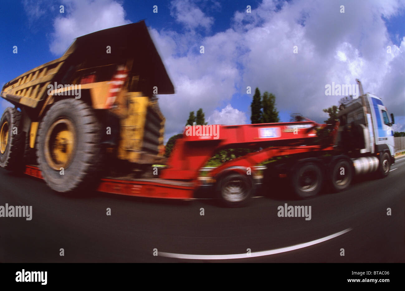 low loader lorry carrying heavy giant truck on trailer travelling on ...