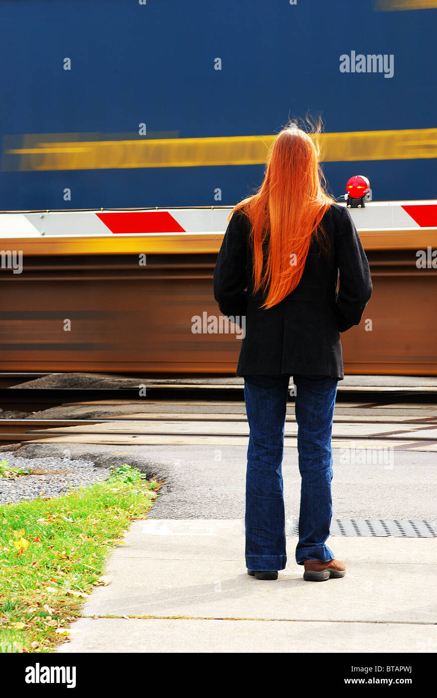 Girl waits for freight train to pass intersection Stock Photo - Alamy