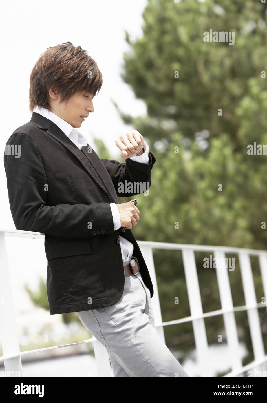Young man leaning on railing Stock Photo - Alamy