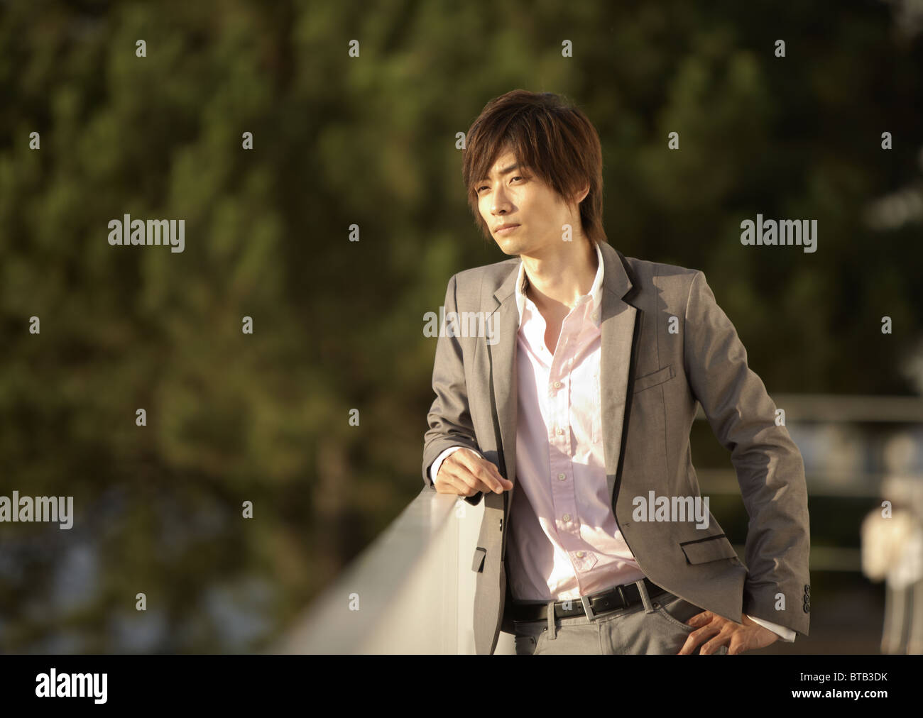 Young man leaning on railing Stock Photo - Alamy