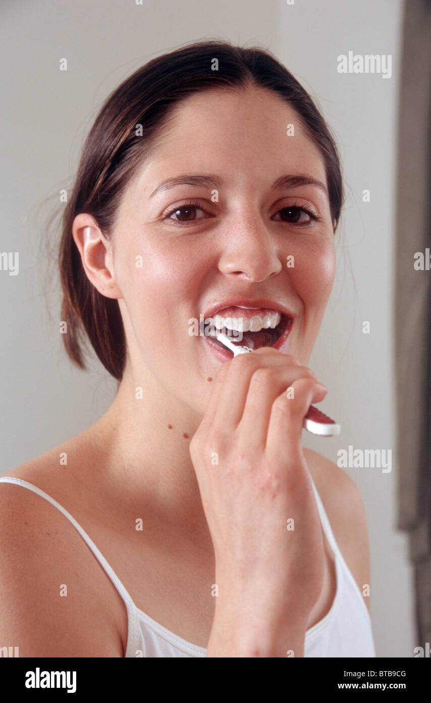 Woman brushing teeth, smiling into the camera Stock Photo - Alamy