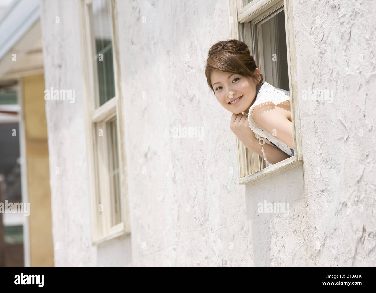 Young woman leaning out of window Stock Photo - Alamy