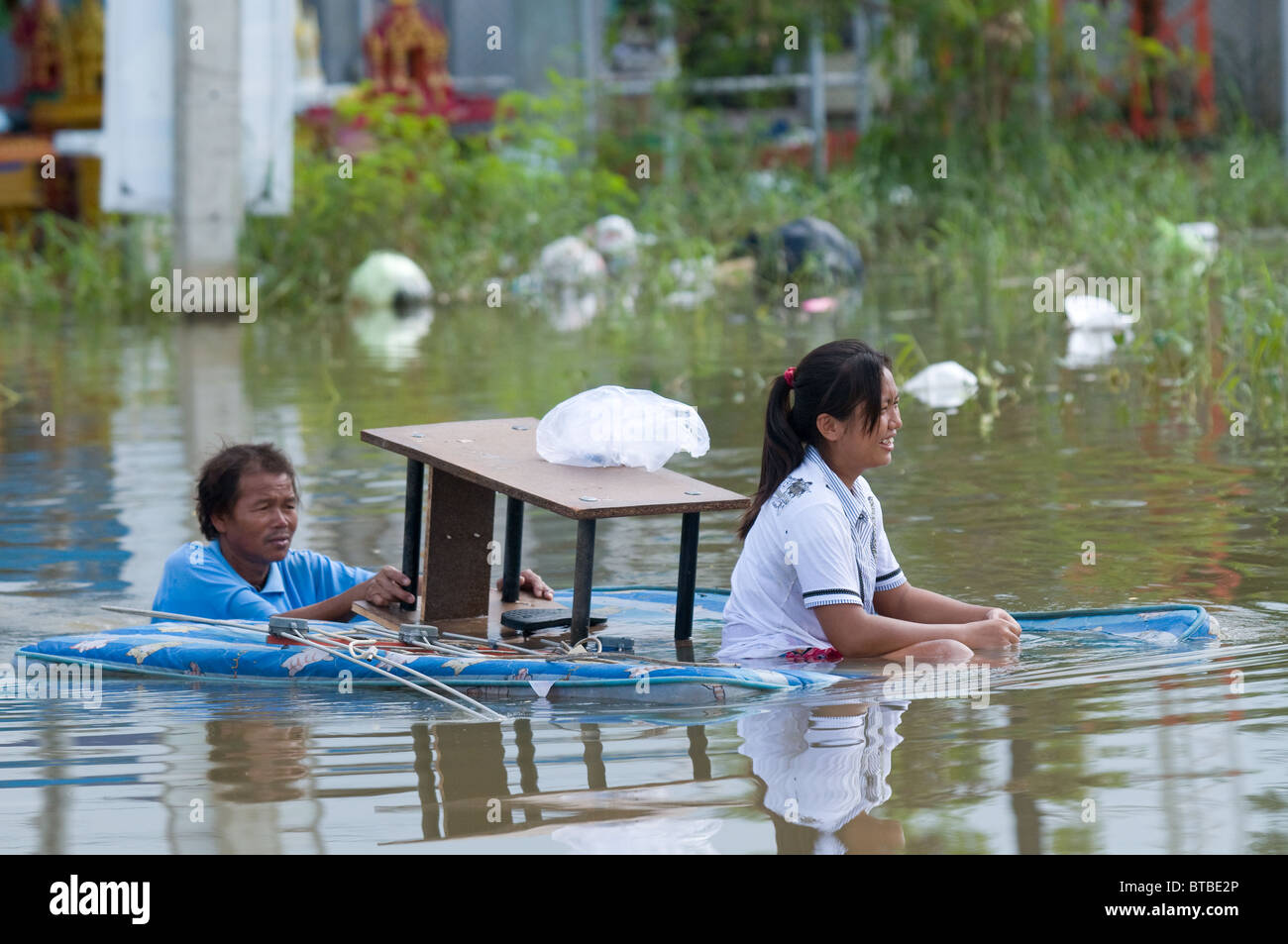 Couple floating through deep water on a village road with a raft made ...