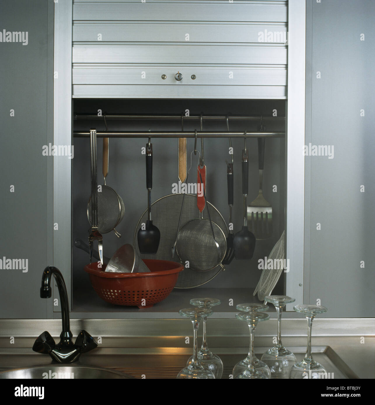 Close-up of sieve and utensils in cupboard with tambour shutter Stock ...