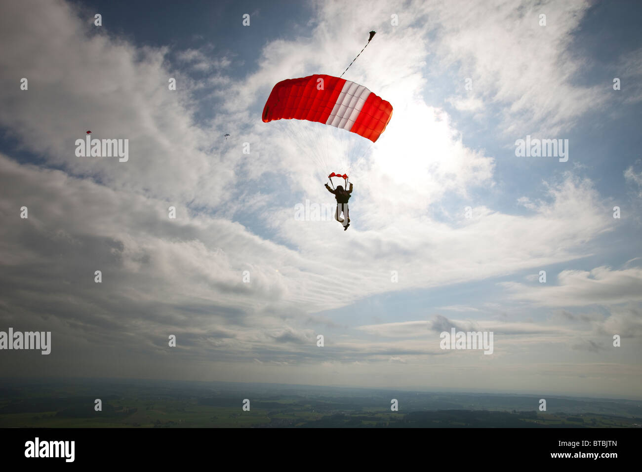 Skydiver parachuting over green fields hi-res stock photography and ...