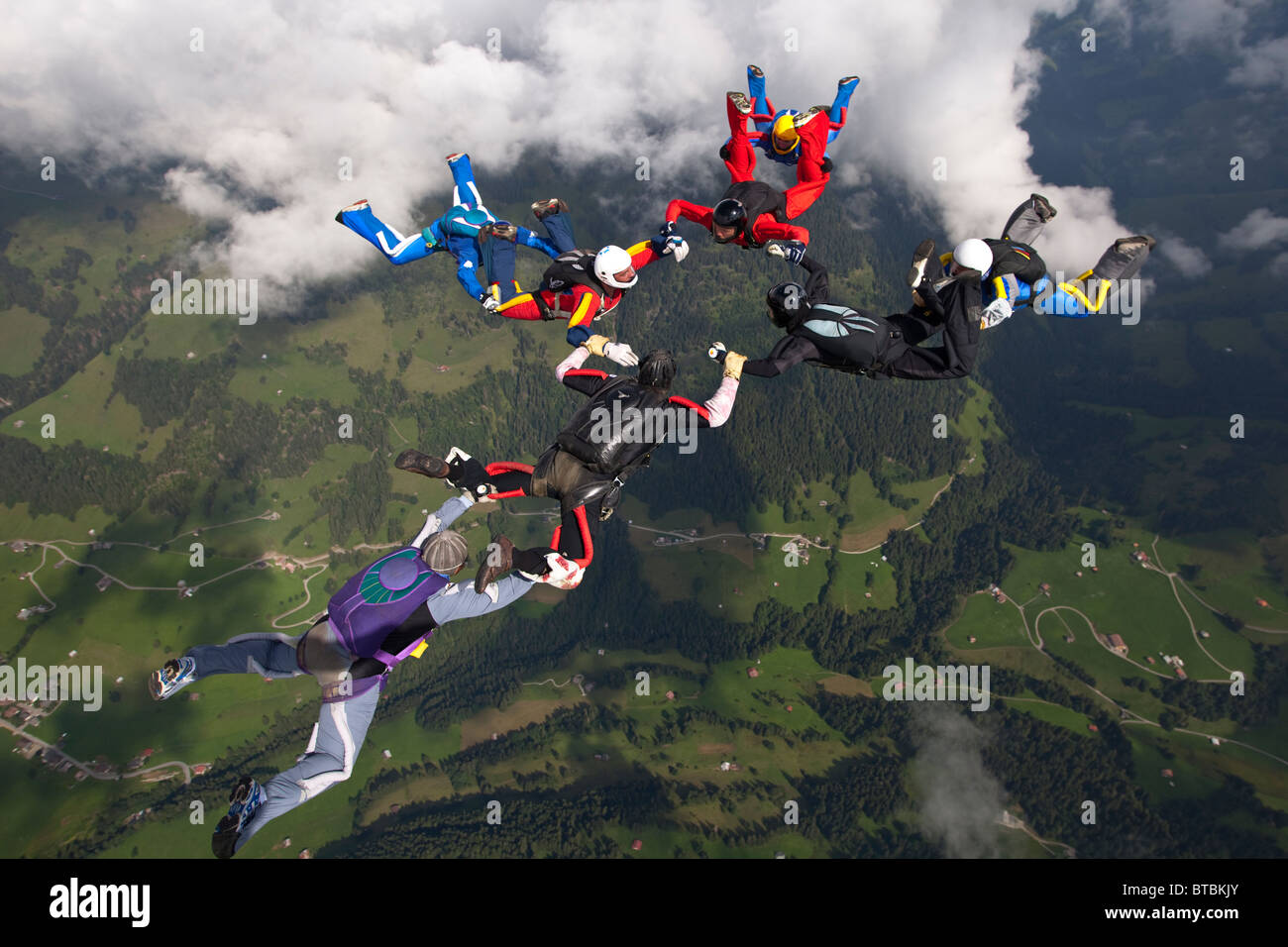Skydivers are flying together in a formation and holding hands with ...
