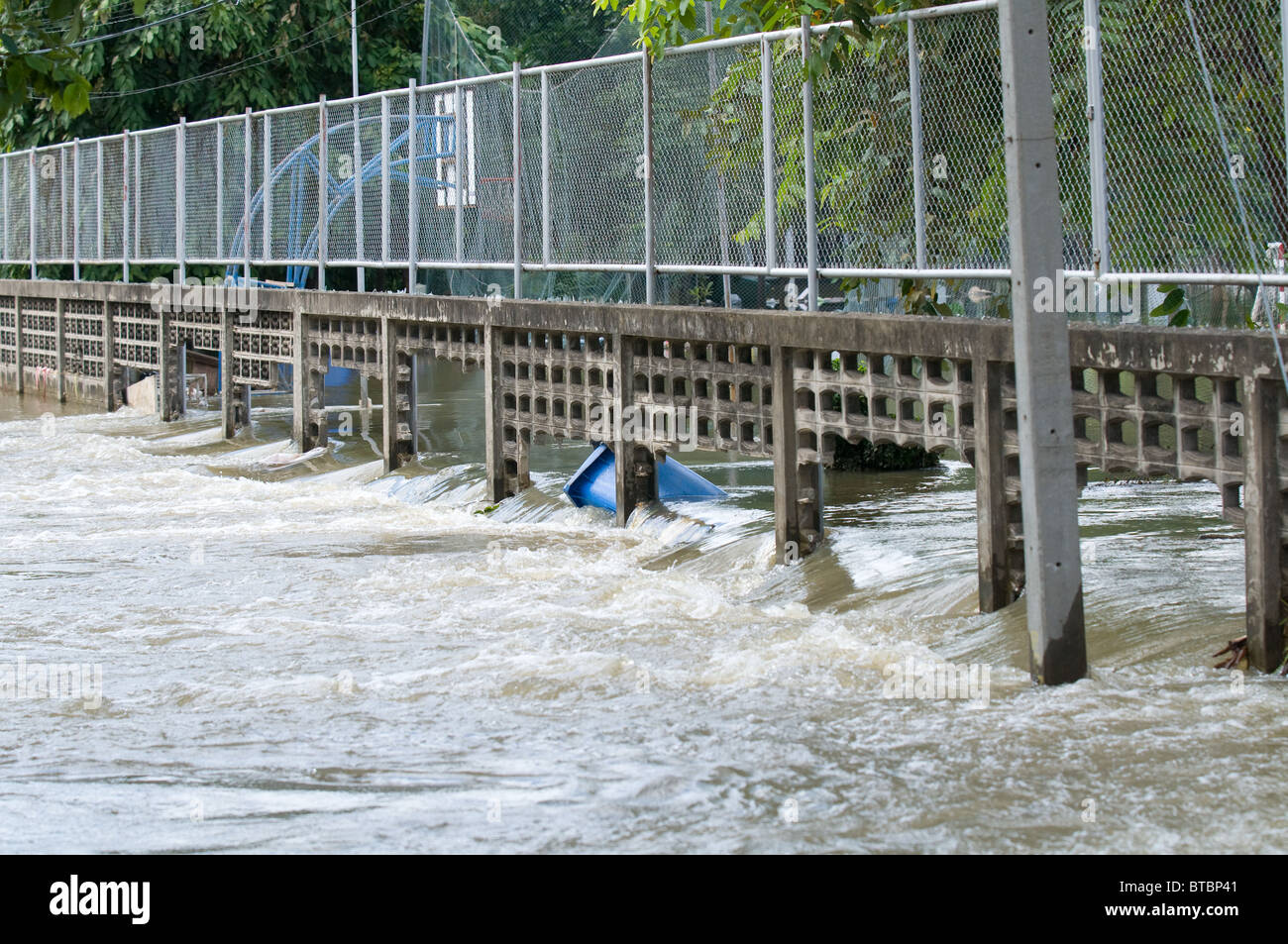 Water flowing through a broken fence during a flood in Nakhon ...