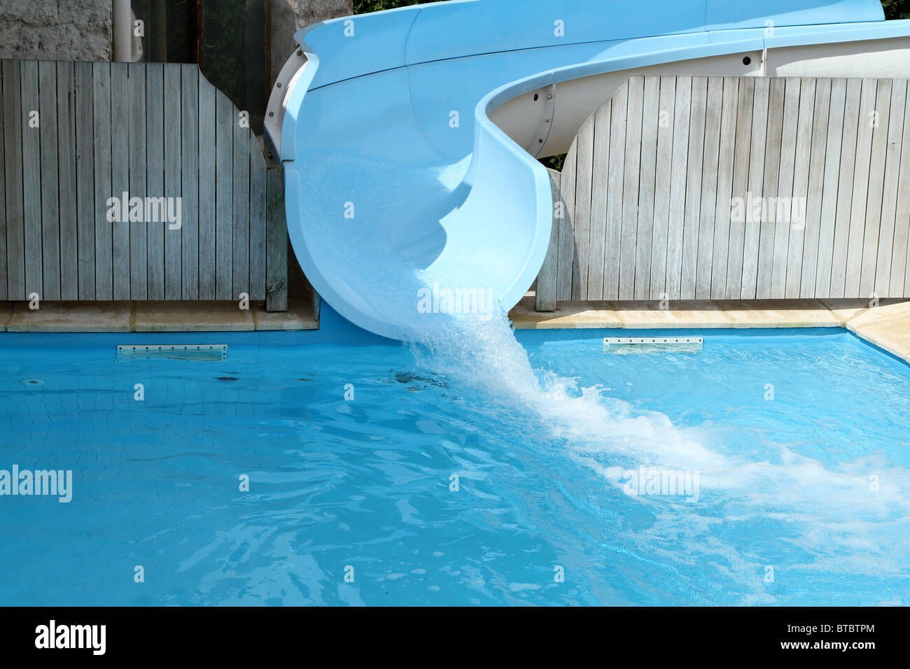 Exit flume of a blue waterslide splashing into a swimming pool Stock ...