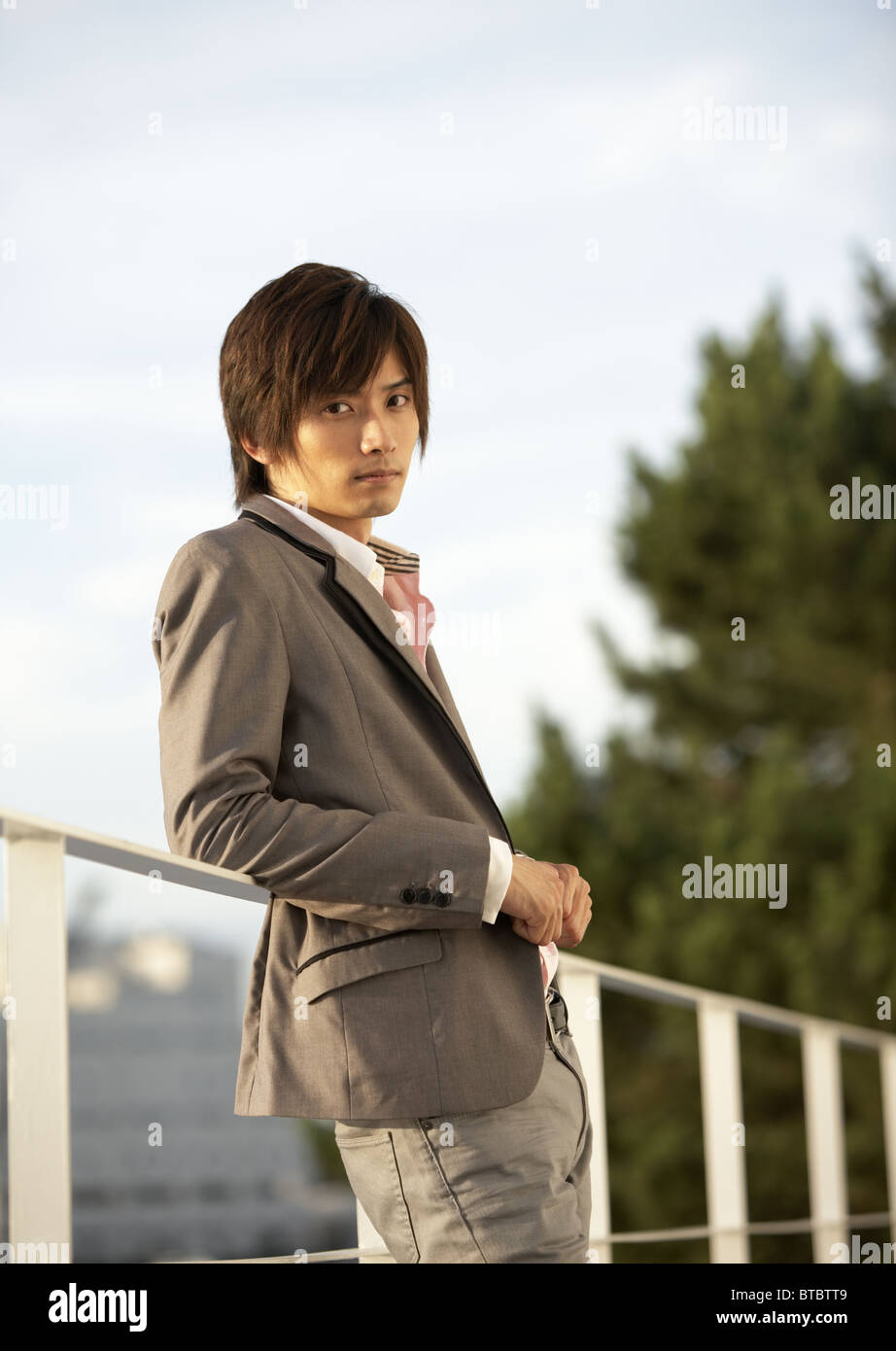 Young man leaning on railing Stock Photo - Alamy