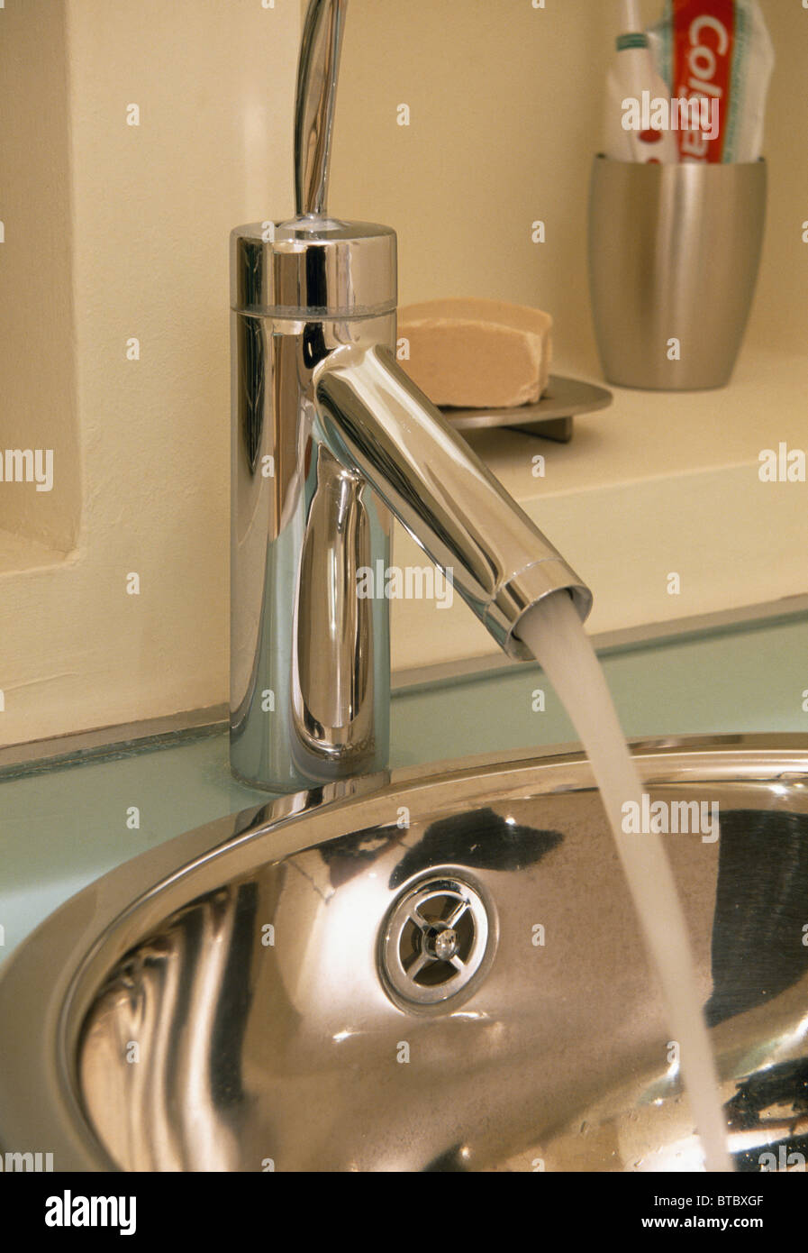 Close-up of modern chrome tap pouring into stainless steel basin Stock ...