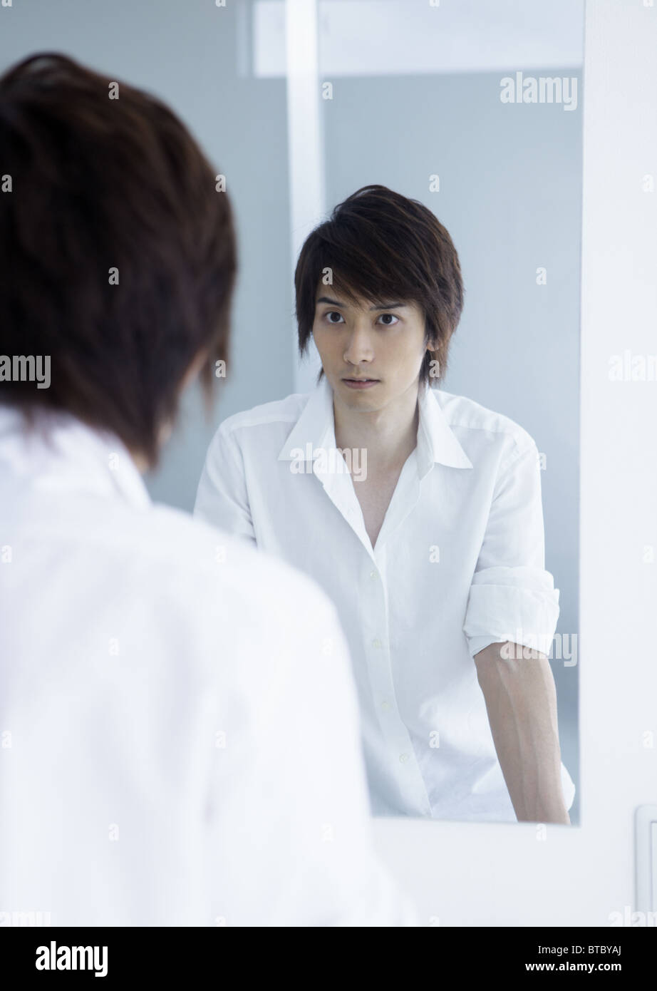 Young man looking in mirror Stock Photo - Alamy