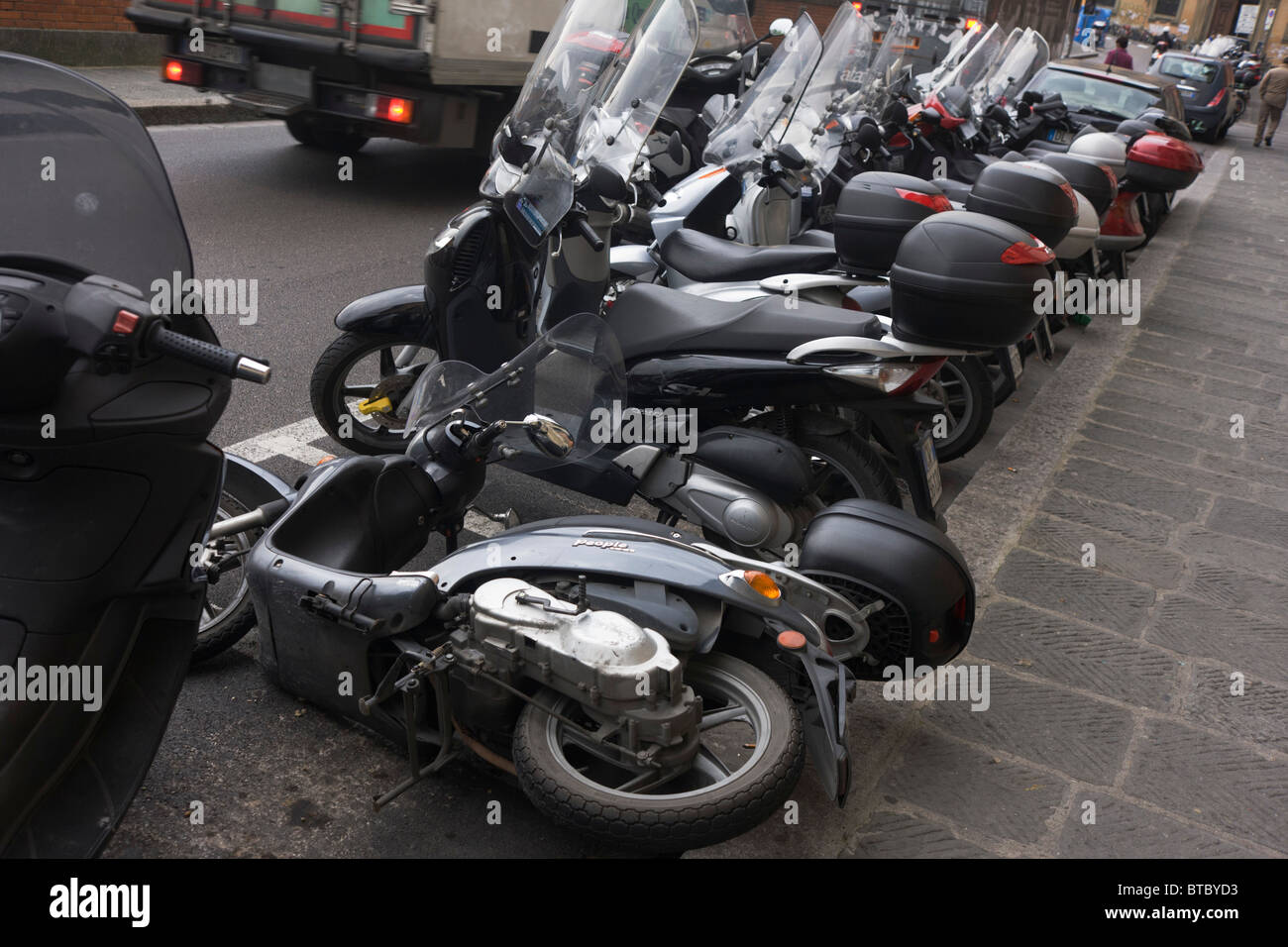 Fallen over motorbike in line of mopeds on Florence street Stock Photo ...
