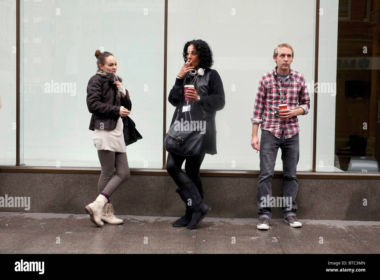 Young workers taking a smoking break in Central London standing outside ...