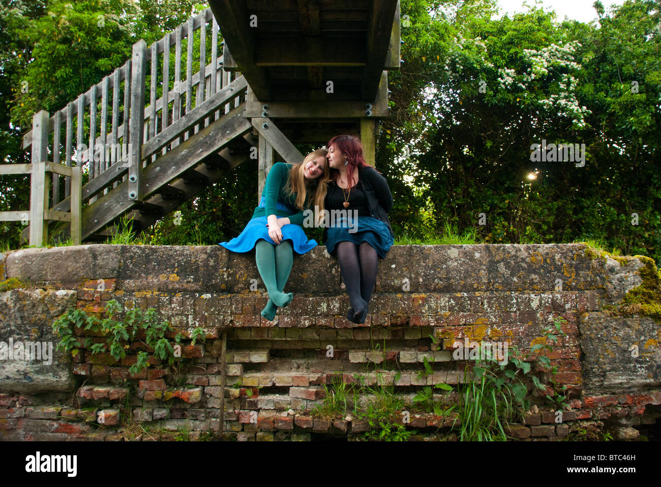 Two young women sitting underneath a bridge Stock Photo - Alamy