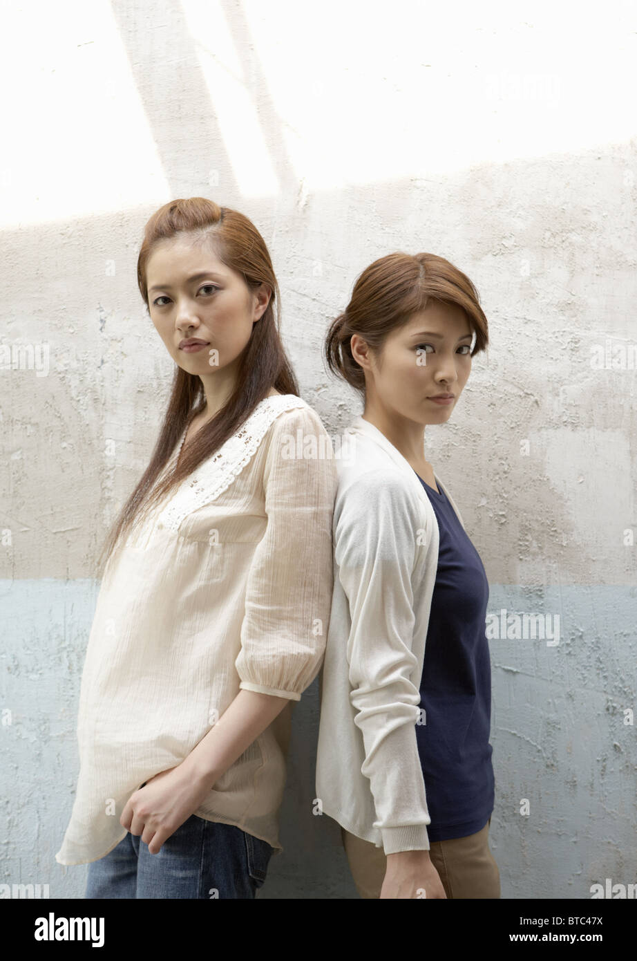 Two women standing back to back Stock Photo - Alamy