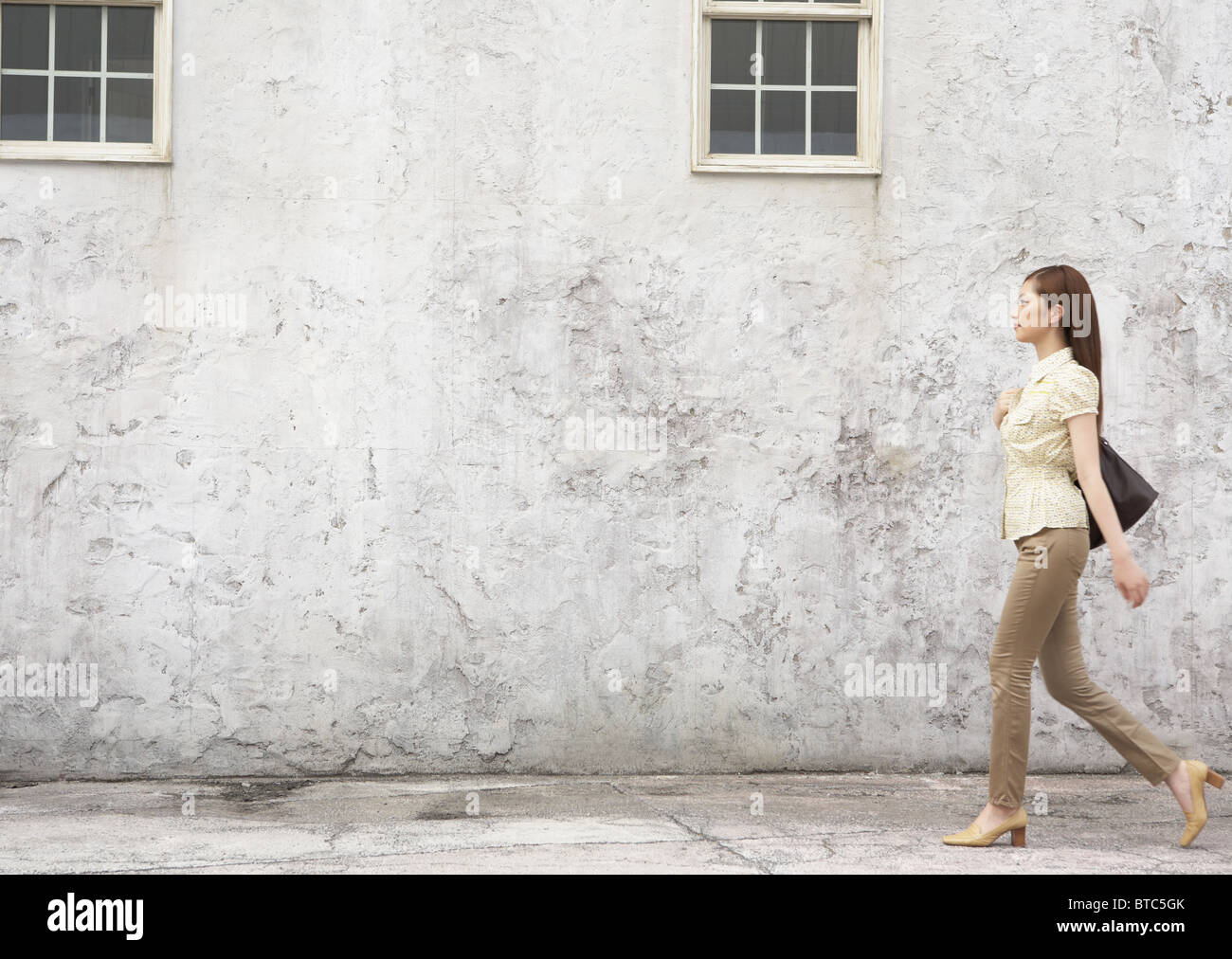 Woman walking in front of wall Stock Photo - Alamy