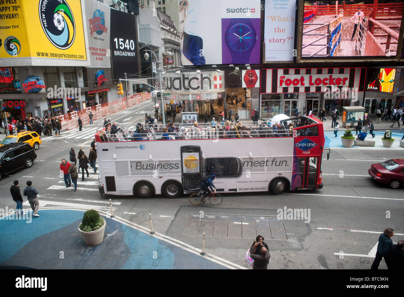 A sightseeing bus maneuvers the traffic patterns in Times Square on ...