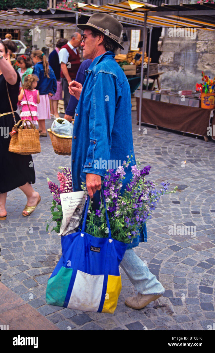 Detail scene of a French street market with shopper carrying flowers ...