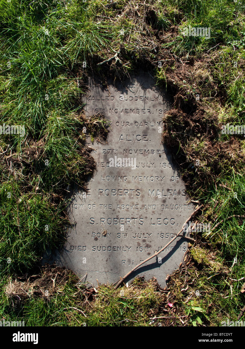 Collapsed headstone with grass encroaching Stock Photo - Alamy