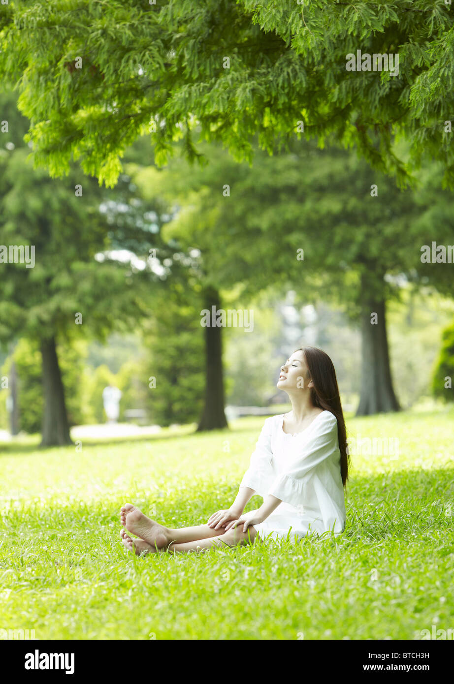 Young woman sitting on grass Stock Photo - Alamy