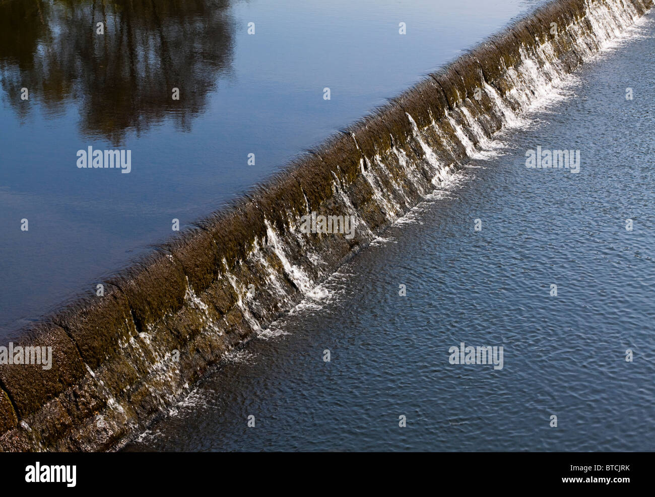 Close up view of a weir on a river with water flowing Stock Photo - Alamy
