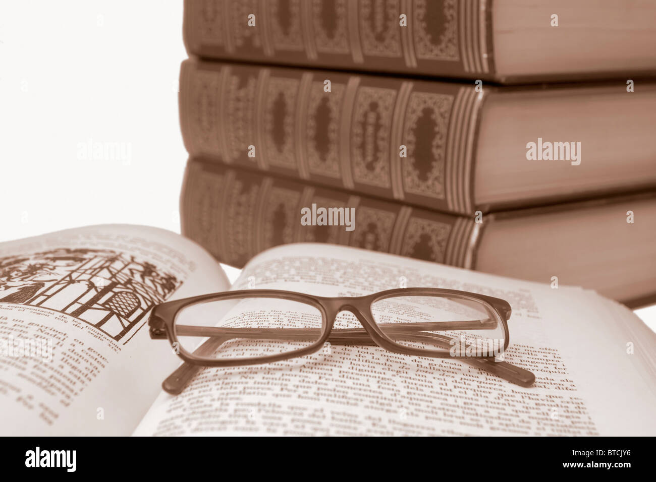 Glasses over opened old book with blurred old books in the background ...
