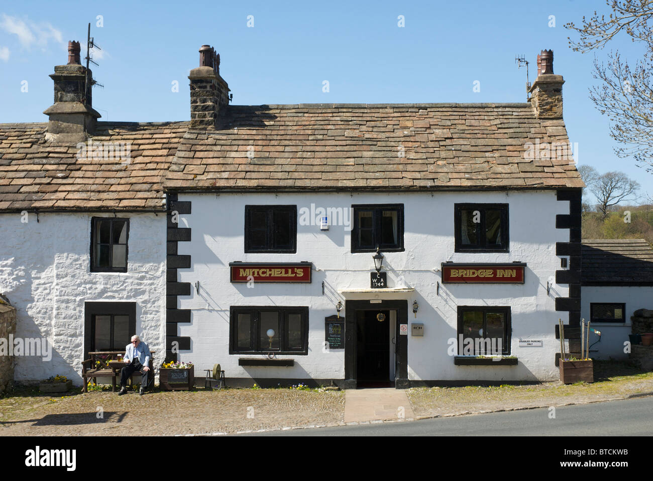 Man sitting outside the Bridge Inn, Tatham, Lancashire, England UK ...