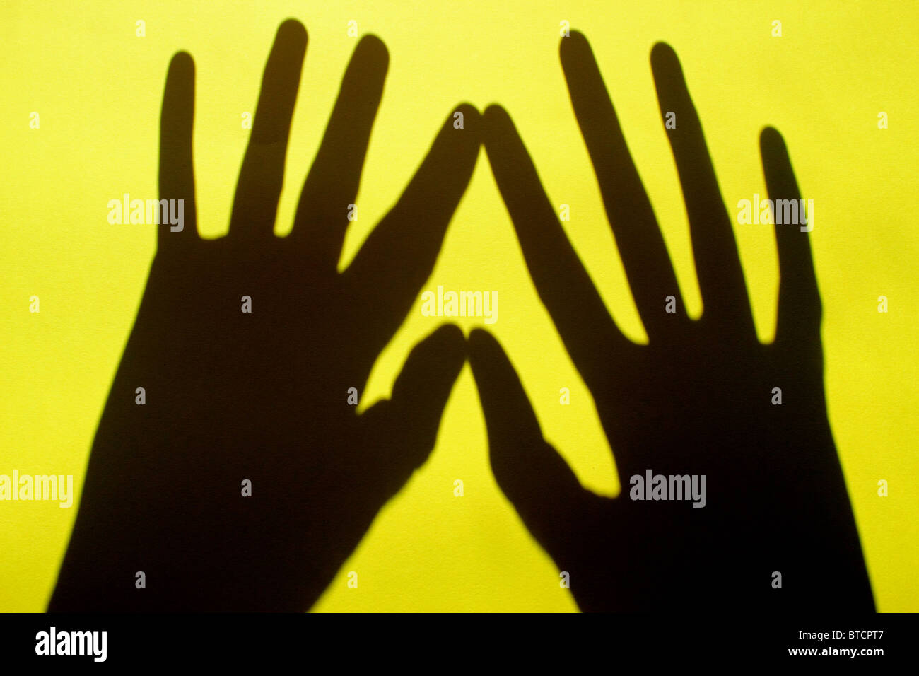Two hand shadows touching on a bright yellow background Stock Photo - Alamy