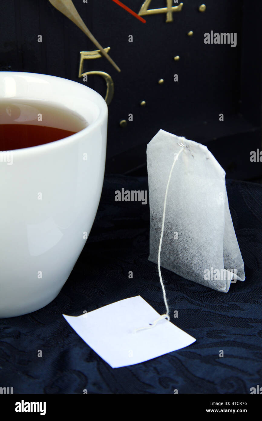 Big black clock and a cup of tea Stock Photo - Alamy