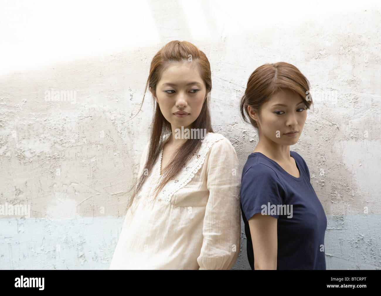 Two women standing back to back Stock Photo - Alamy