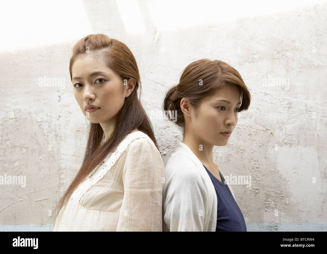 Two women standing back to back Stock Photo - Alamy