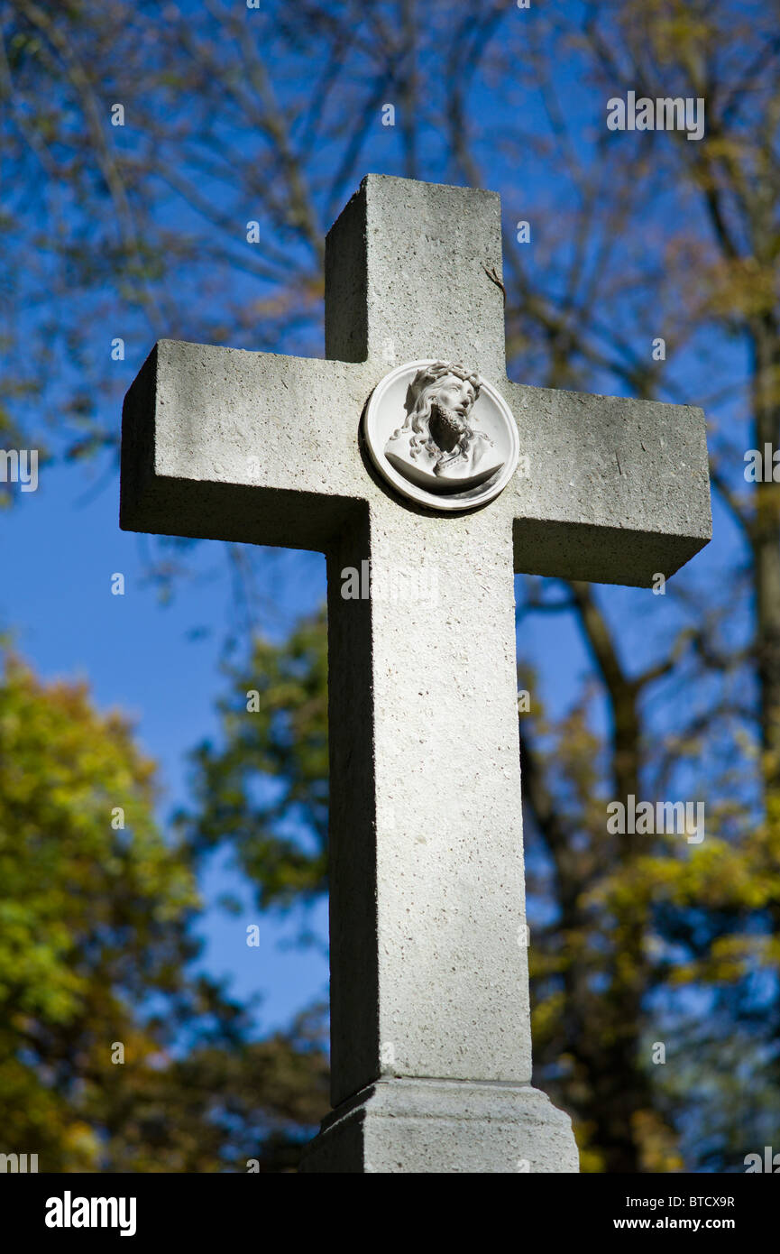 Grey stone cross with a relief of Jesus on a graveyard in Munich ...