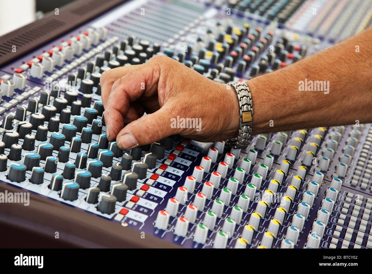 a tight close up of a sound engineer adjusting the controls on a multi ...