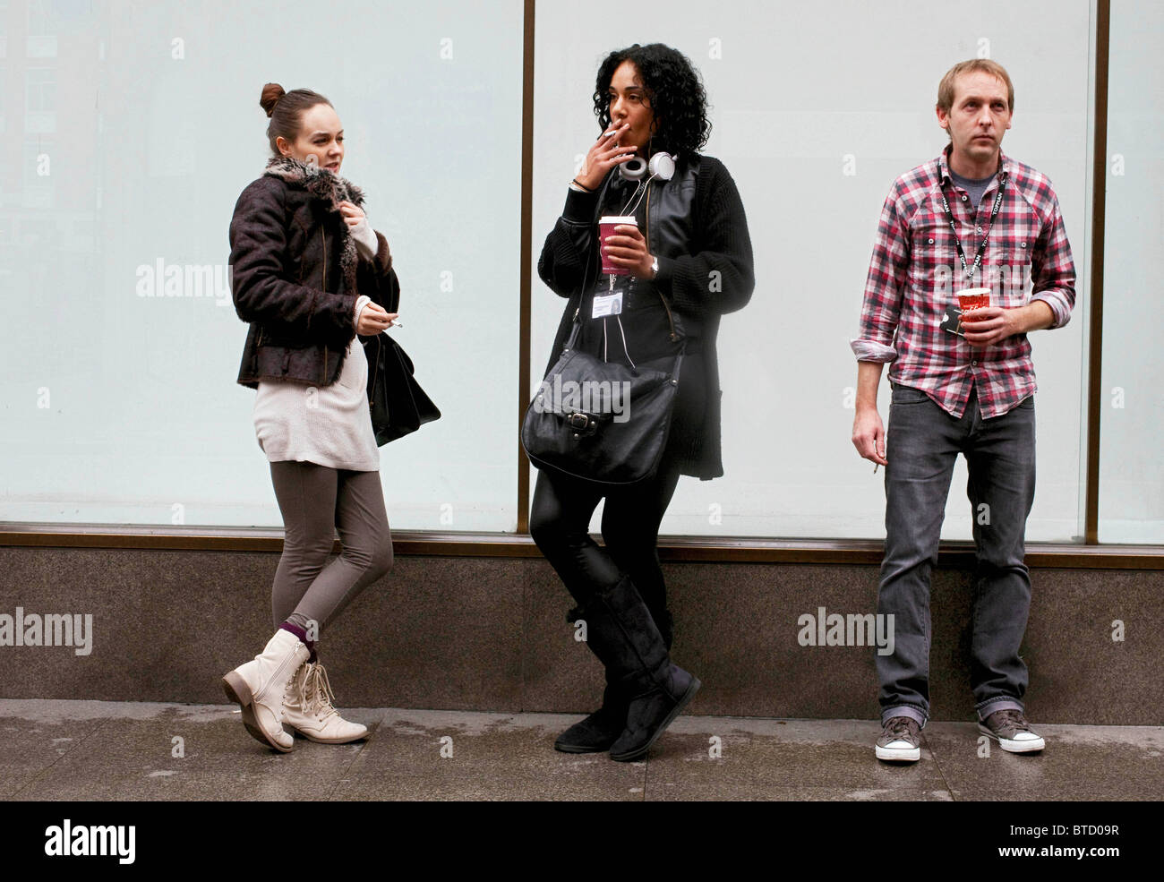 Young workers taking a smoking break in Central London standing outside ...
