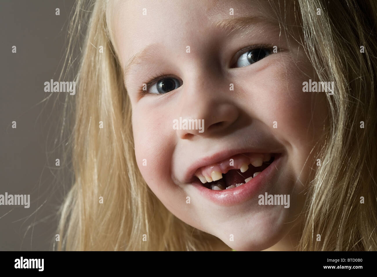 closeup portrait of funny smiling little girl without one front tooth ...