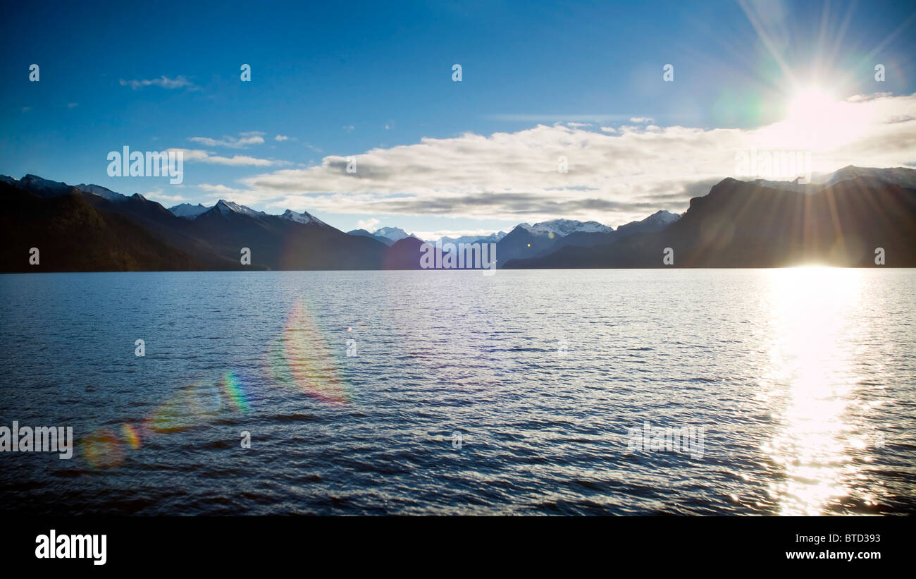 Early morning sun flares over mountain tops and a lake Stock Photo - Alamy