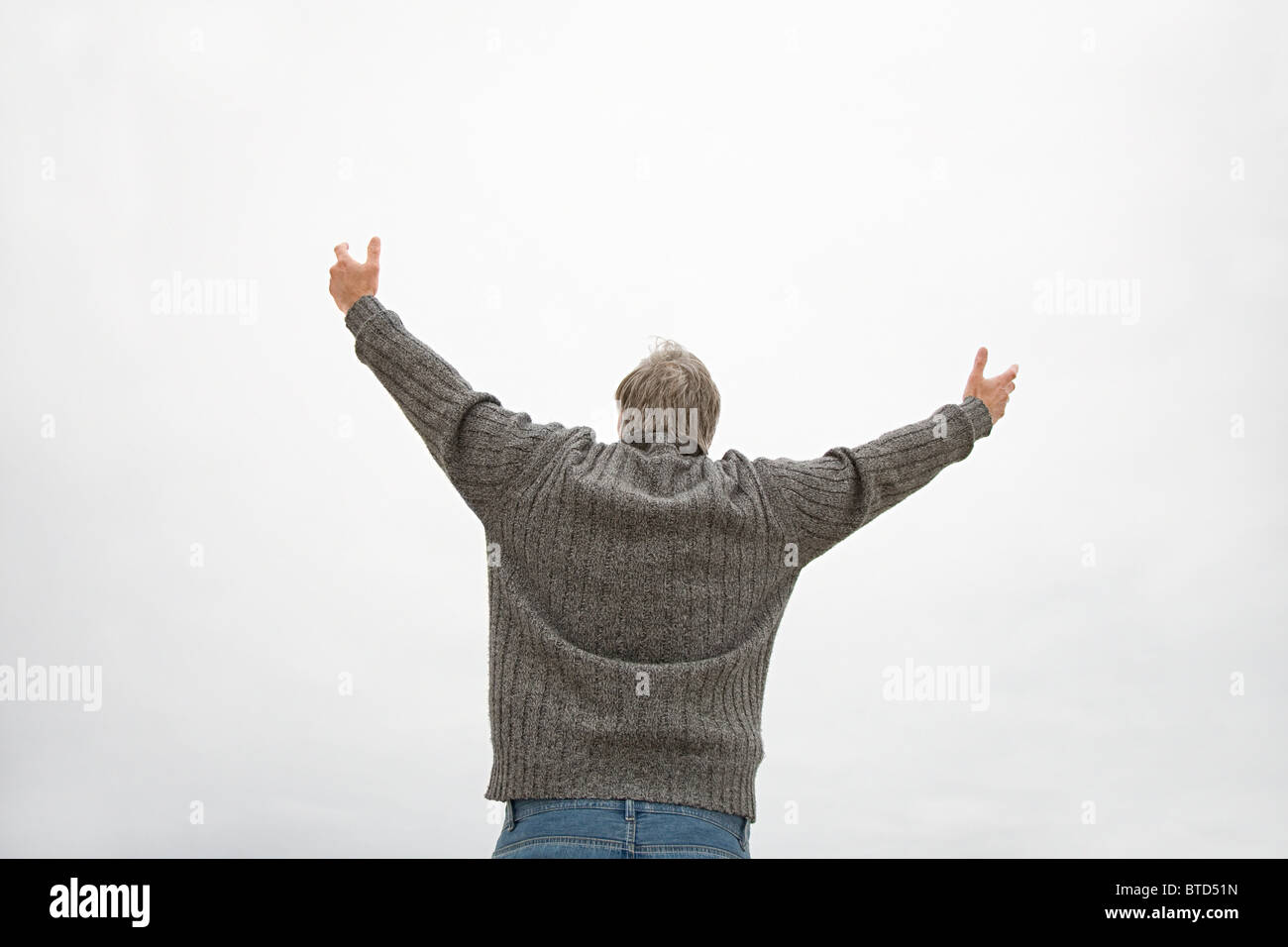 Rear view of man with arms raised Stock Photo - Alamy
