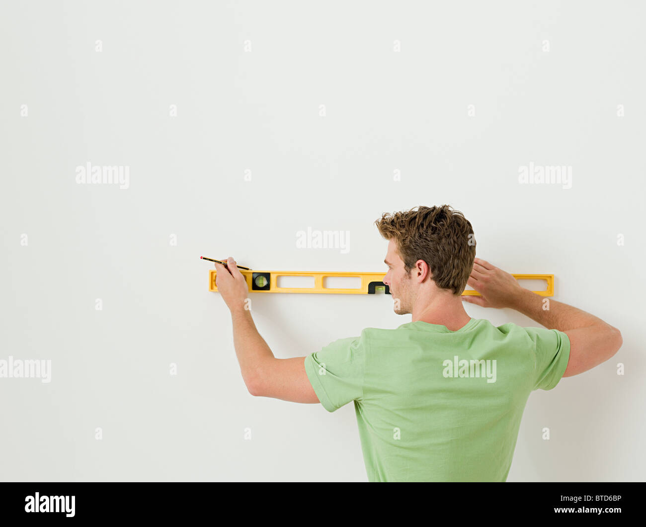 Young man using spirit level on wall Stock Photo - Alamy