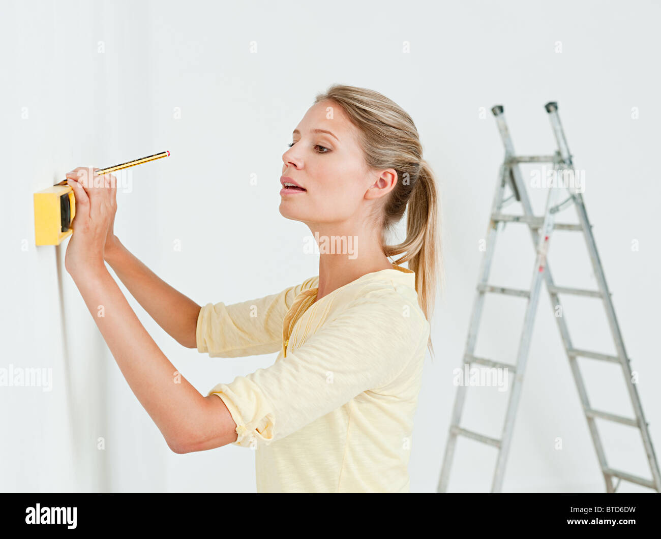 Young woman using spirit level on wall Stock Photo - Alamy