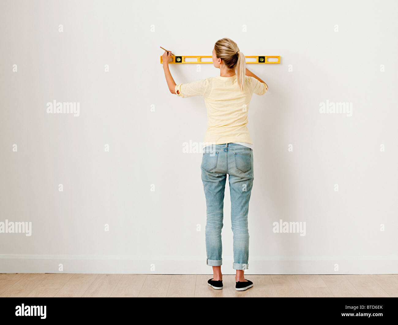 Young woman using spirit level on wall Stock Photo - Alamy