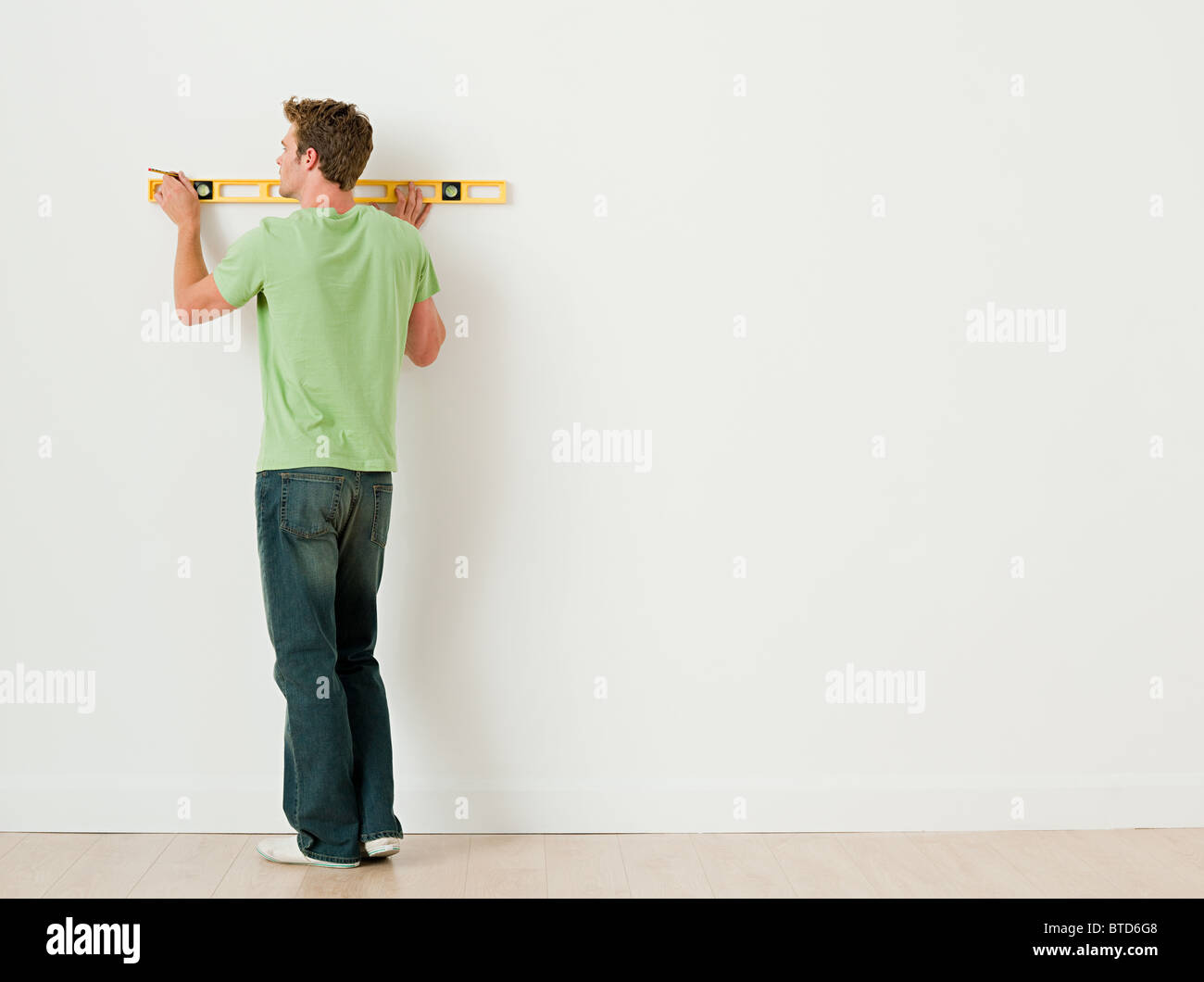 Young man using spirit level on wall Stock Photo - Alamy