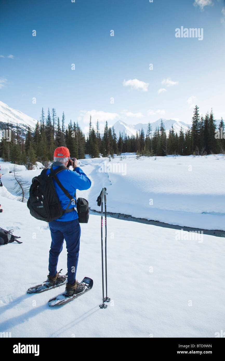 Man on snowshoes views the scenery at Glacier Creek near Johnson Pass ...