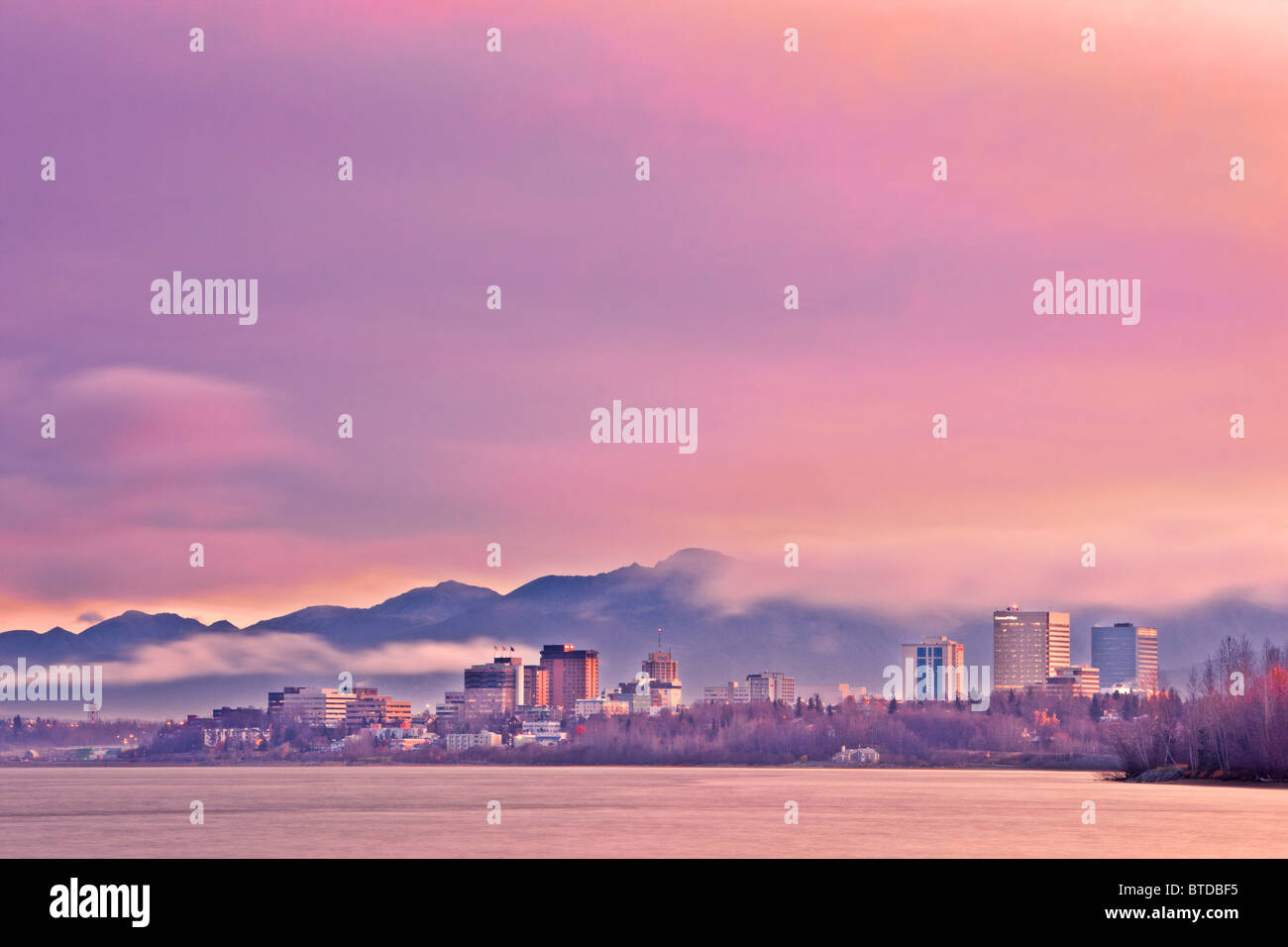 Skyline view of the sun rising over a fog shrouded Anchorage and Cook ...